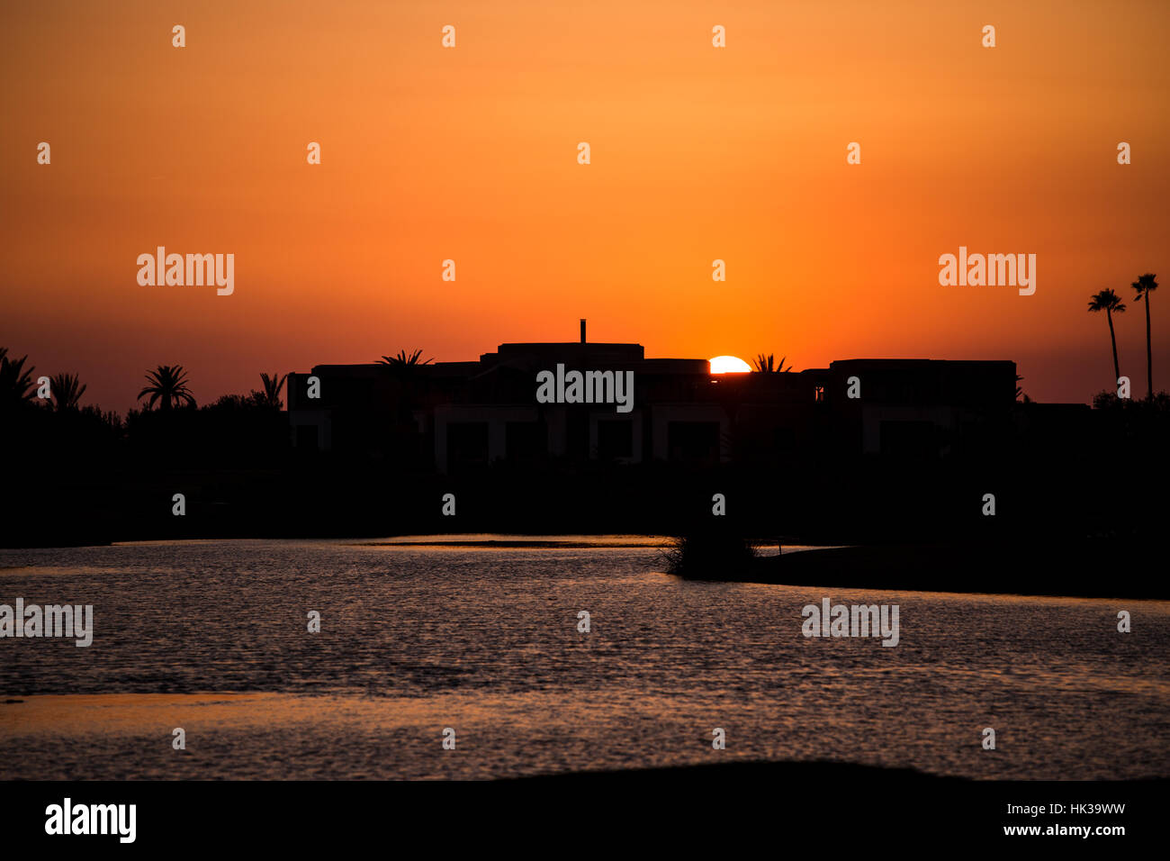 Sunset behind buildings and lake reflection Stock Photo - Alamy