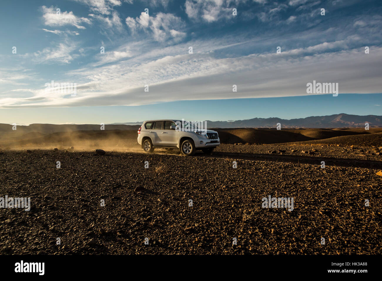 Wide shot of SUV Toyota Prado driving, through the desert of Ouarzazate ...