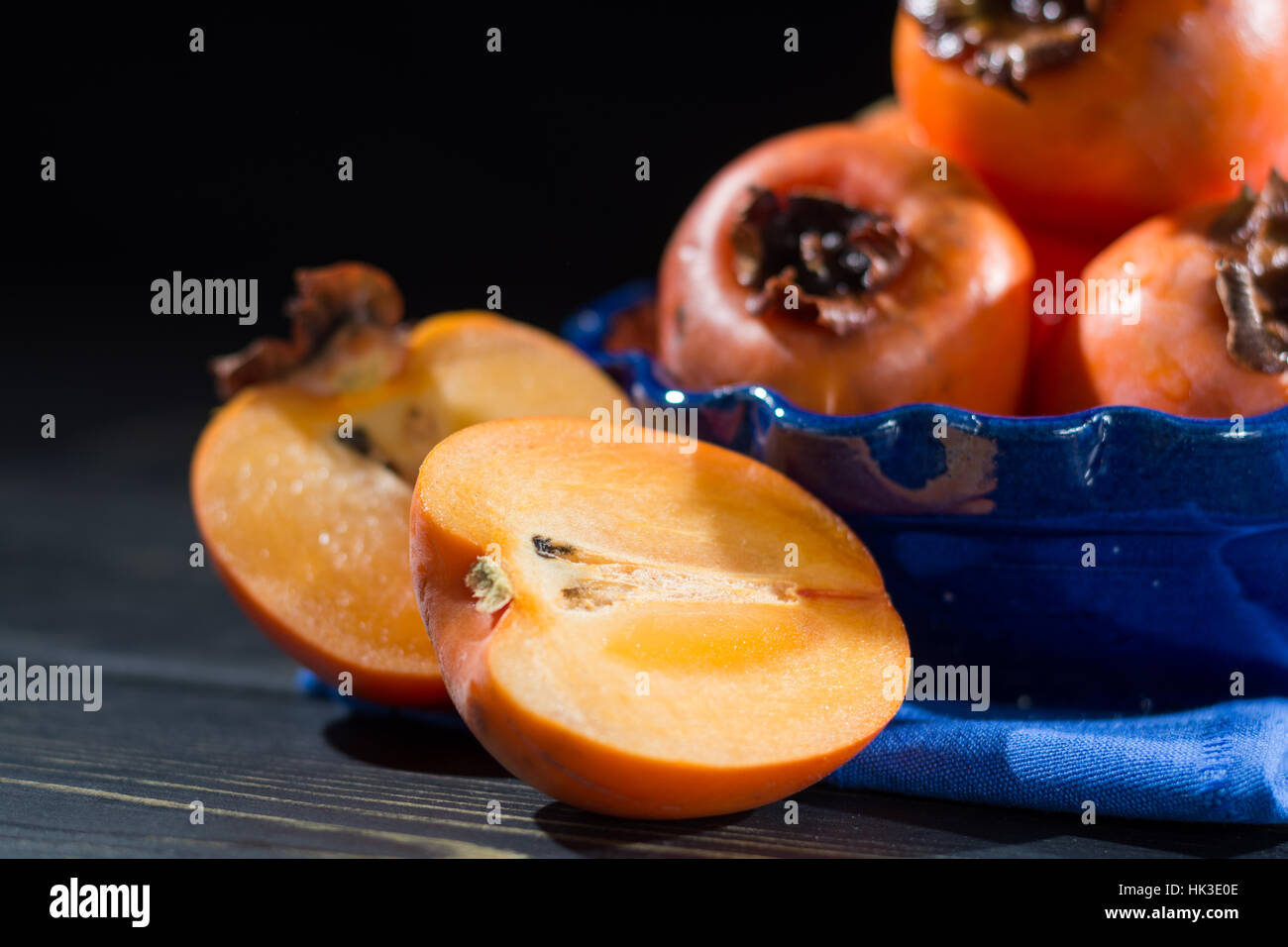Ripe orange hachiya persimmons in blue bowl Stock Photo - Alamy