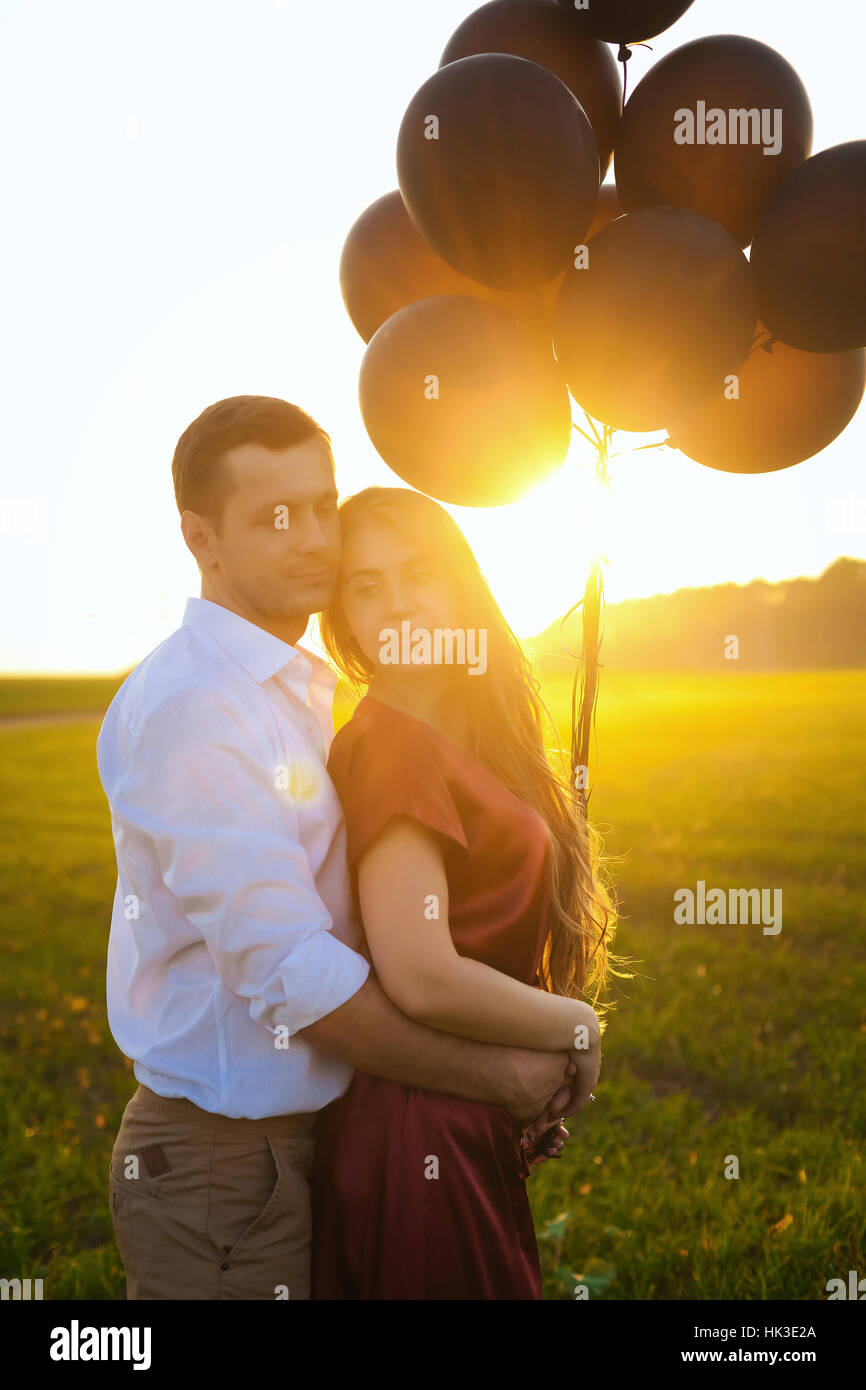 guy in white shirt and girl in red dress hugging at sunset. In their ...