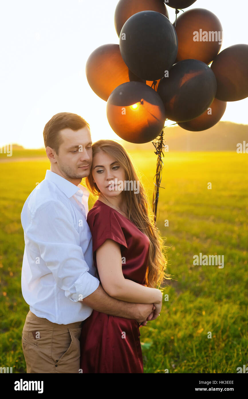 guy in white shirt and girl in red dress hugging at sunset. In their ...