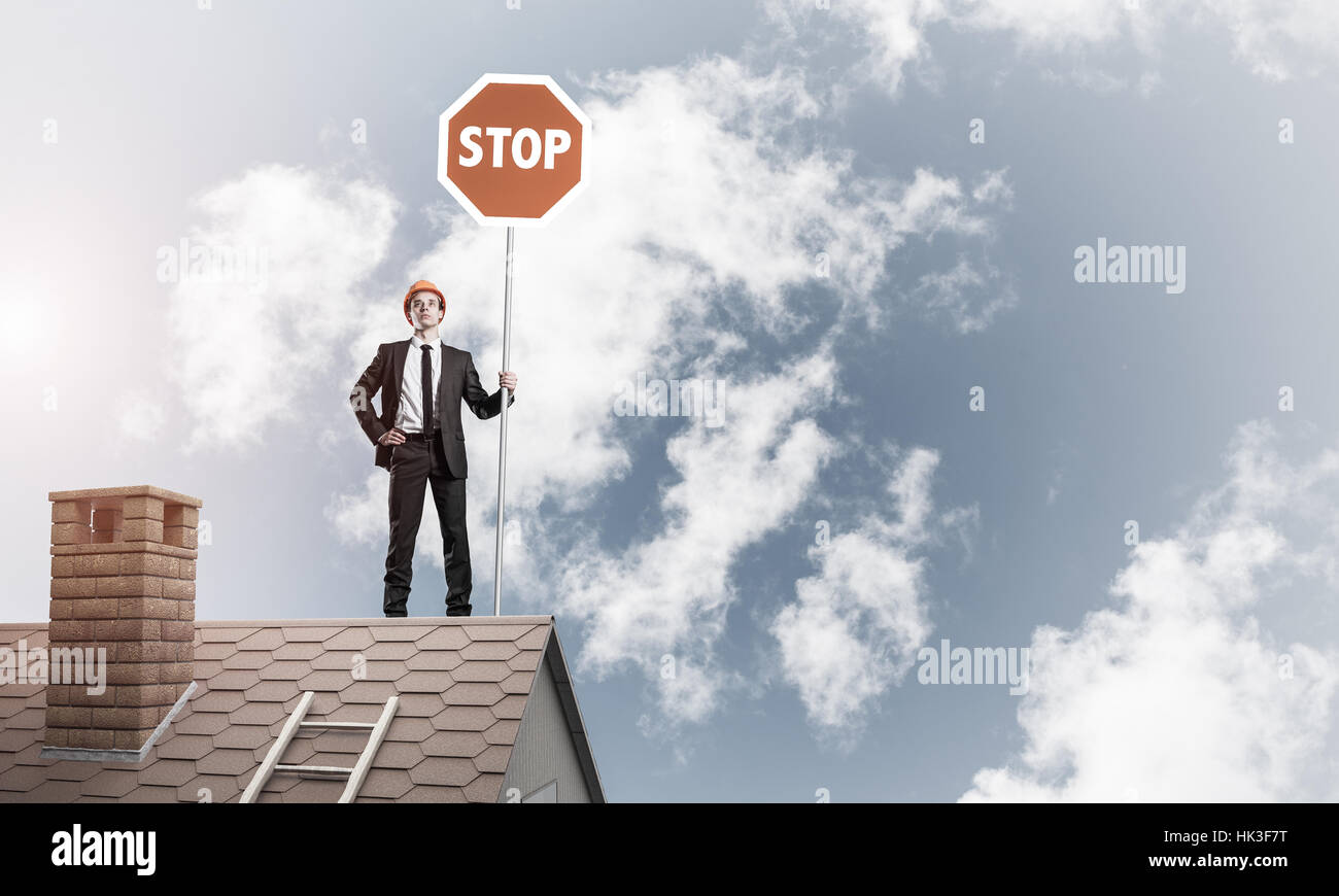Caucasian businessman on brick house roof showing stop road sign Stock ...