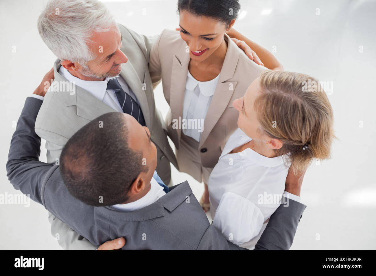 Teamwork embracing together in the workplace Stock Photo - Alamy