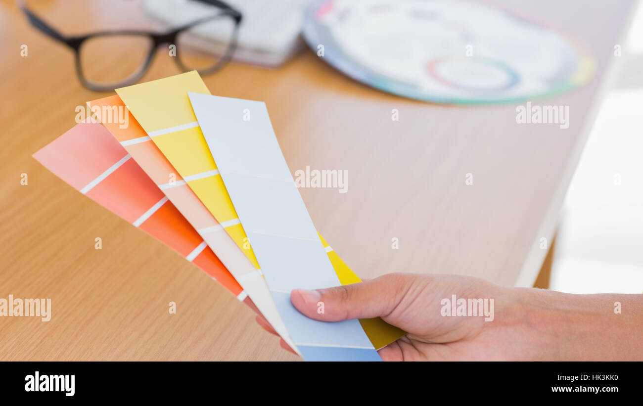 Hand holding colour charts over a desk Stock Photo - Alamy