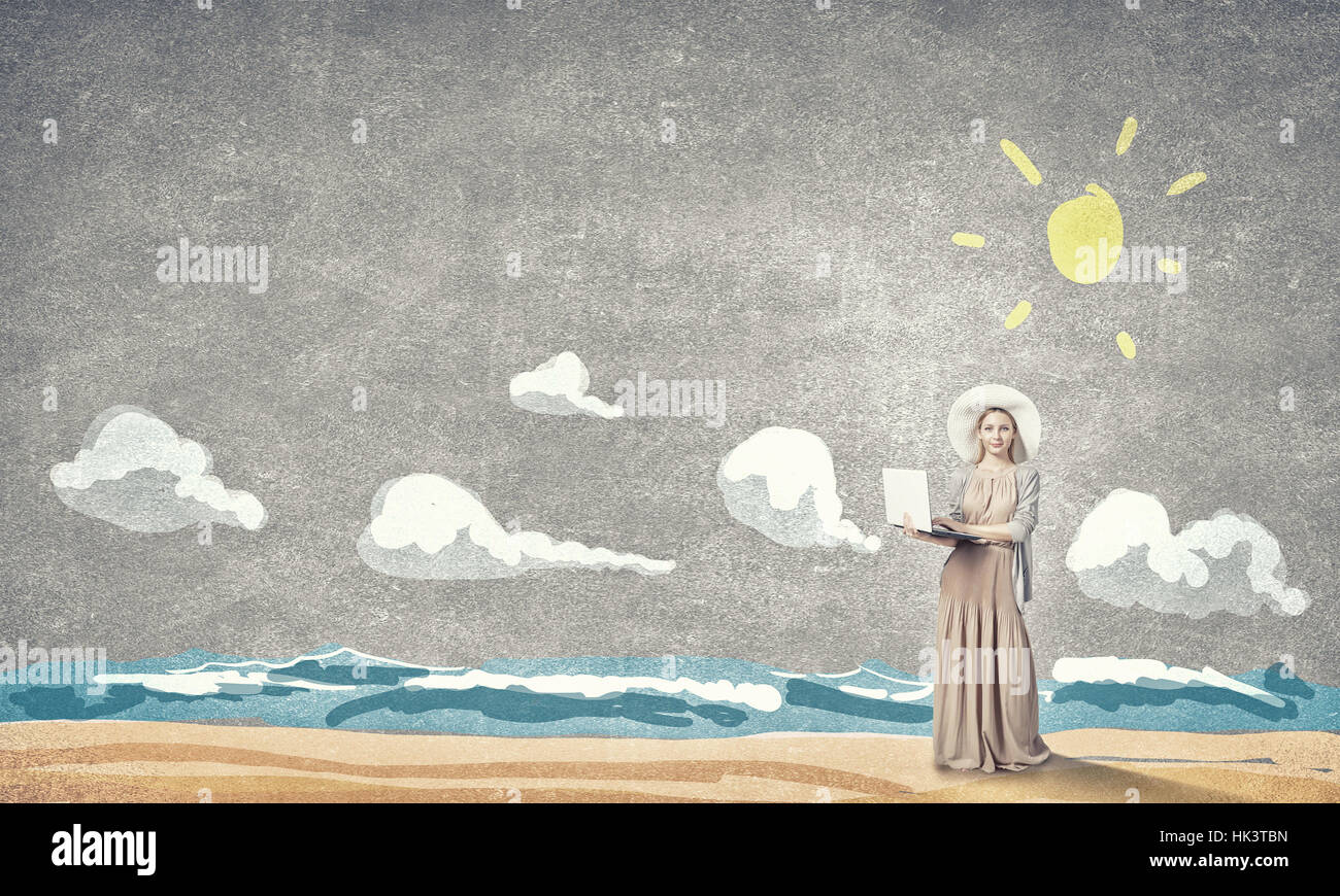 Young lady in hat and long dress using laptop hi-res stock photography ...