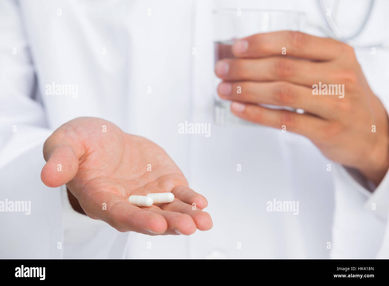Doctor holding tablets and glass of water on white background Stock ...