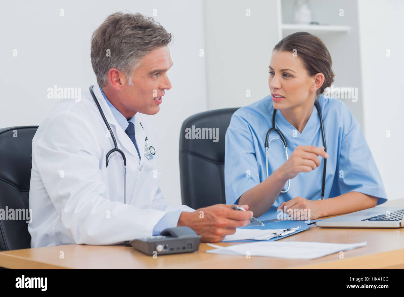 Two doctors discussing and working together in a medical office Stock ...
