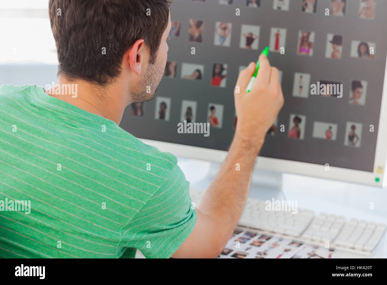 Photo editor pointing at his screen with a green marker in his office ...