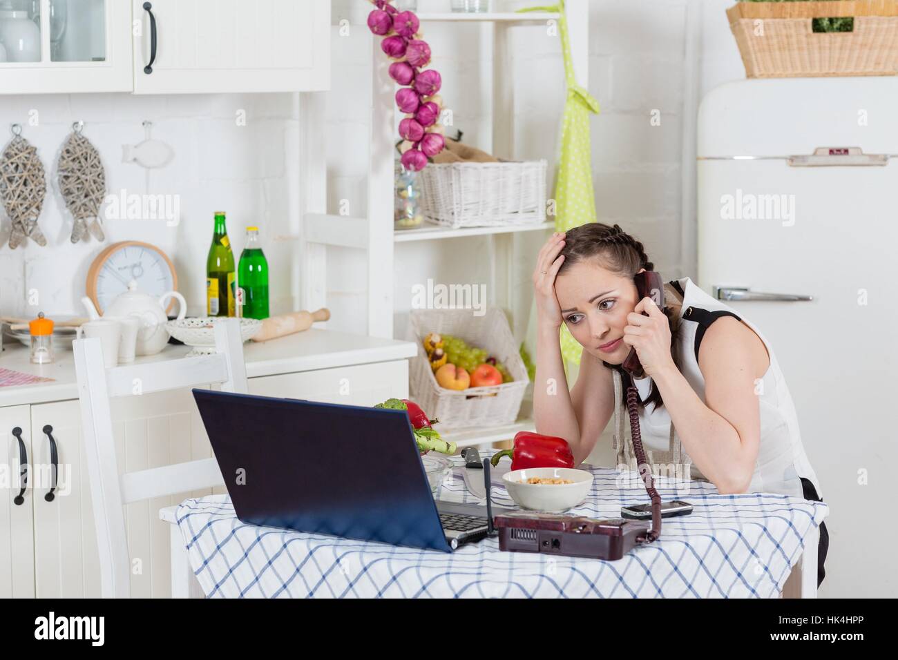 Stressed young woman in an apron with notebook and phone cooks in the ...