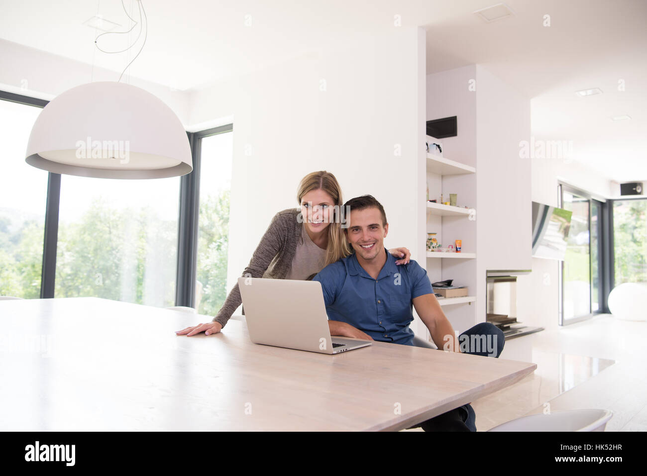 Young couple using laptop computer at luxury home together, looking at ...