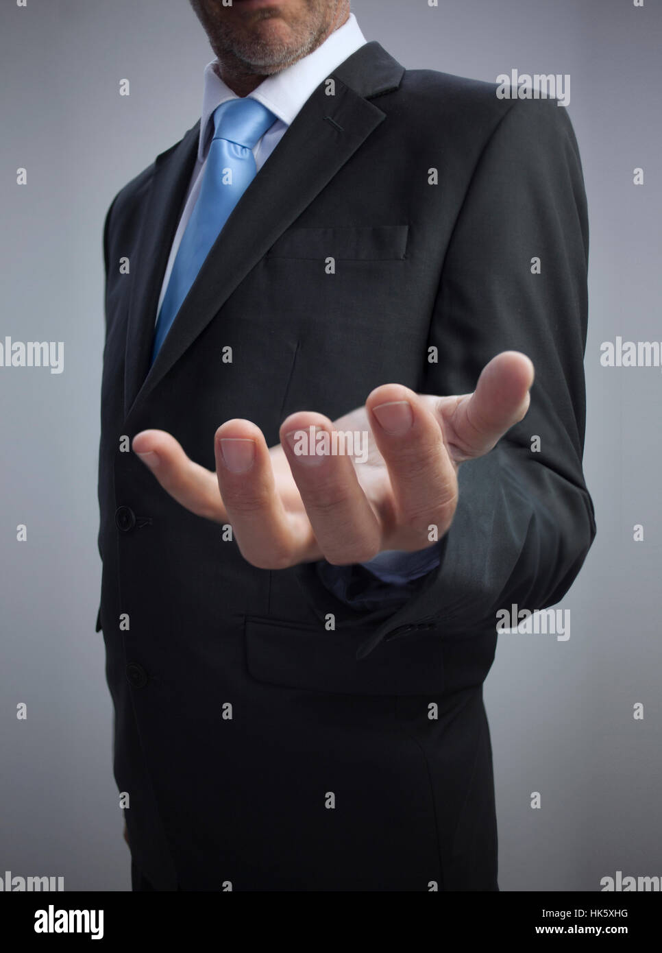 Businessman showing his empty hand against grey background Stock Photo ...