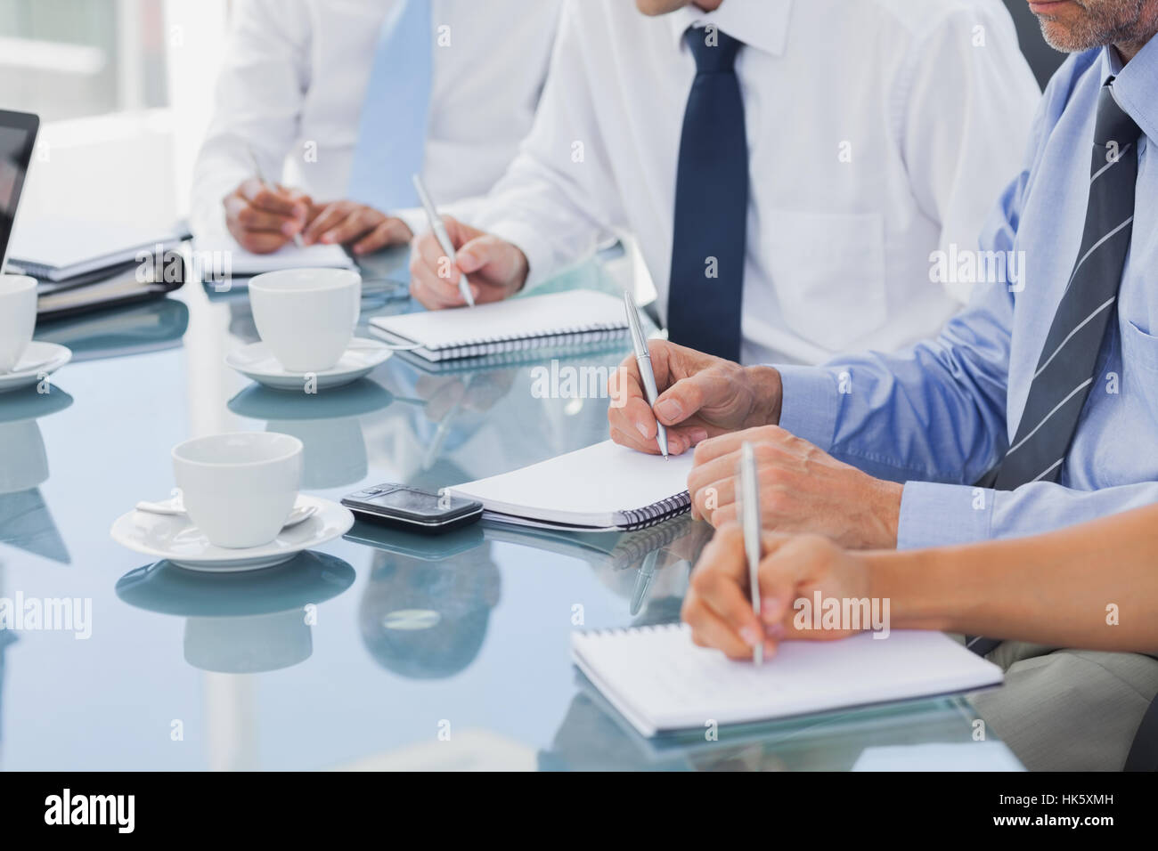 Business people taking notes on notepads during a meeting Stock Photo ...