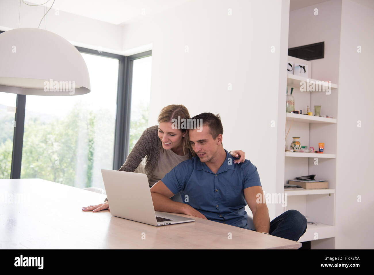 Young couple using laptop computer at luxury home together, looking at ...