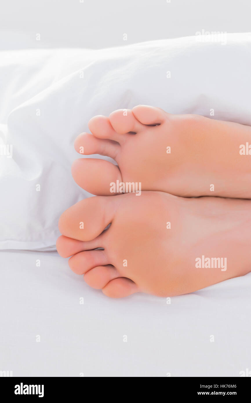 Feet under a duvet in a bed Stock Photo - Alamy