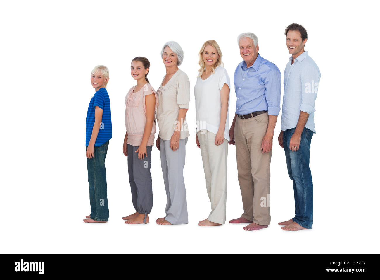 Multi-generation family posing together and looking at camera on white ...