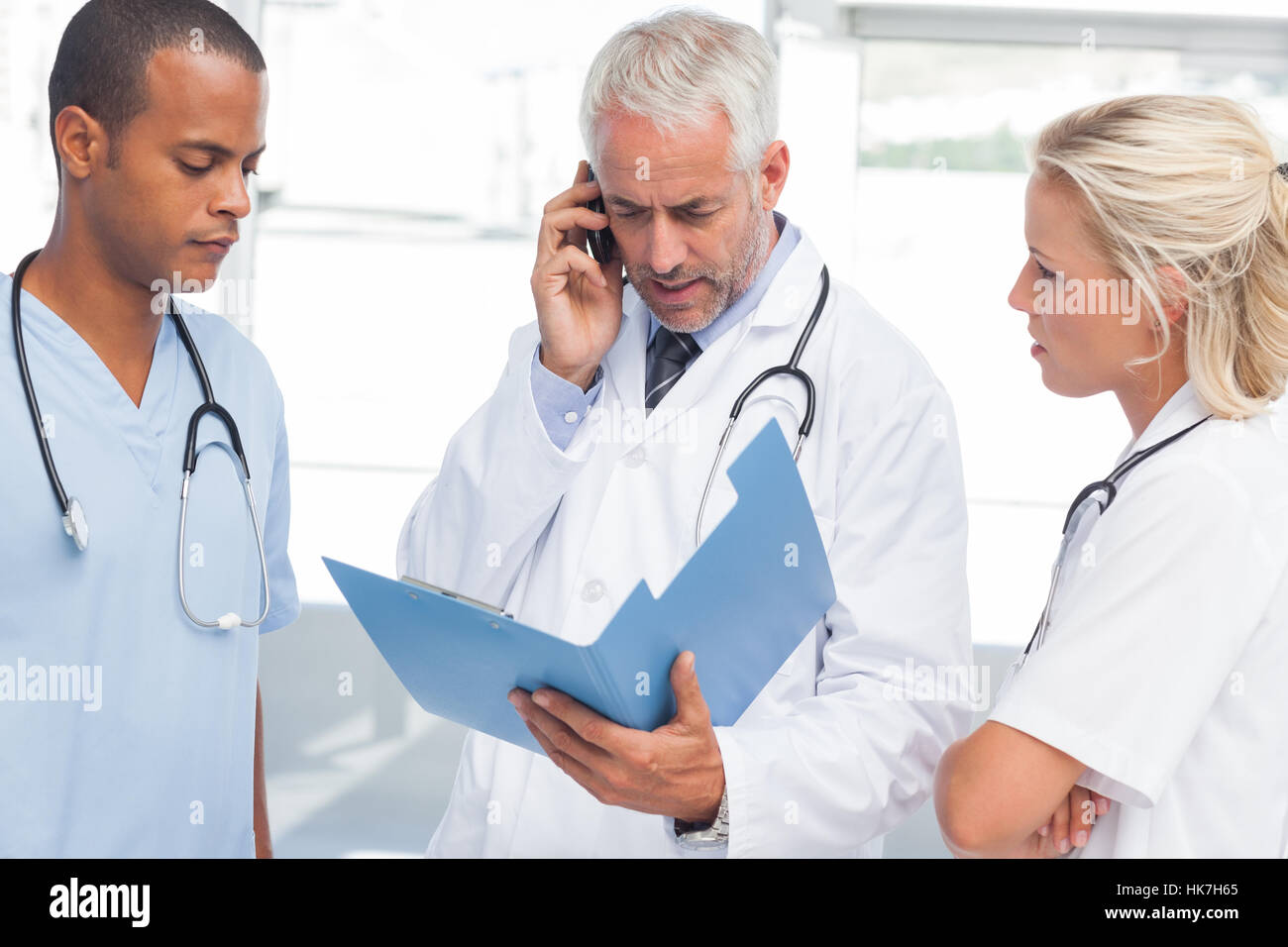 Three worried doctors calling someone Stock Photo - Alamy