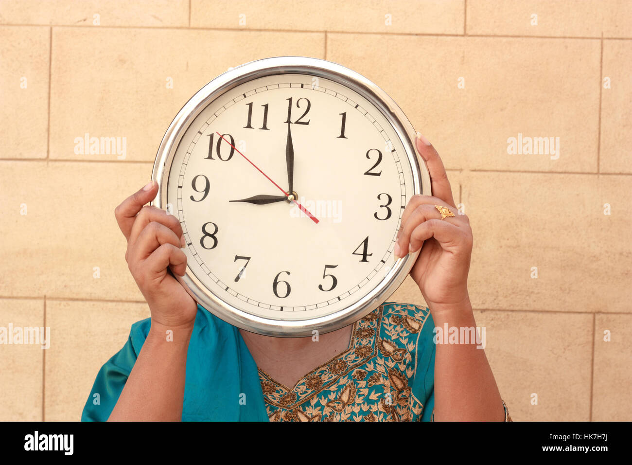 Pakistani female with a clock showing 9 o clock time Stock Photo - Alamy
