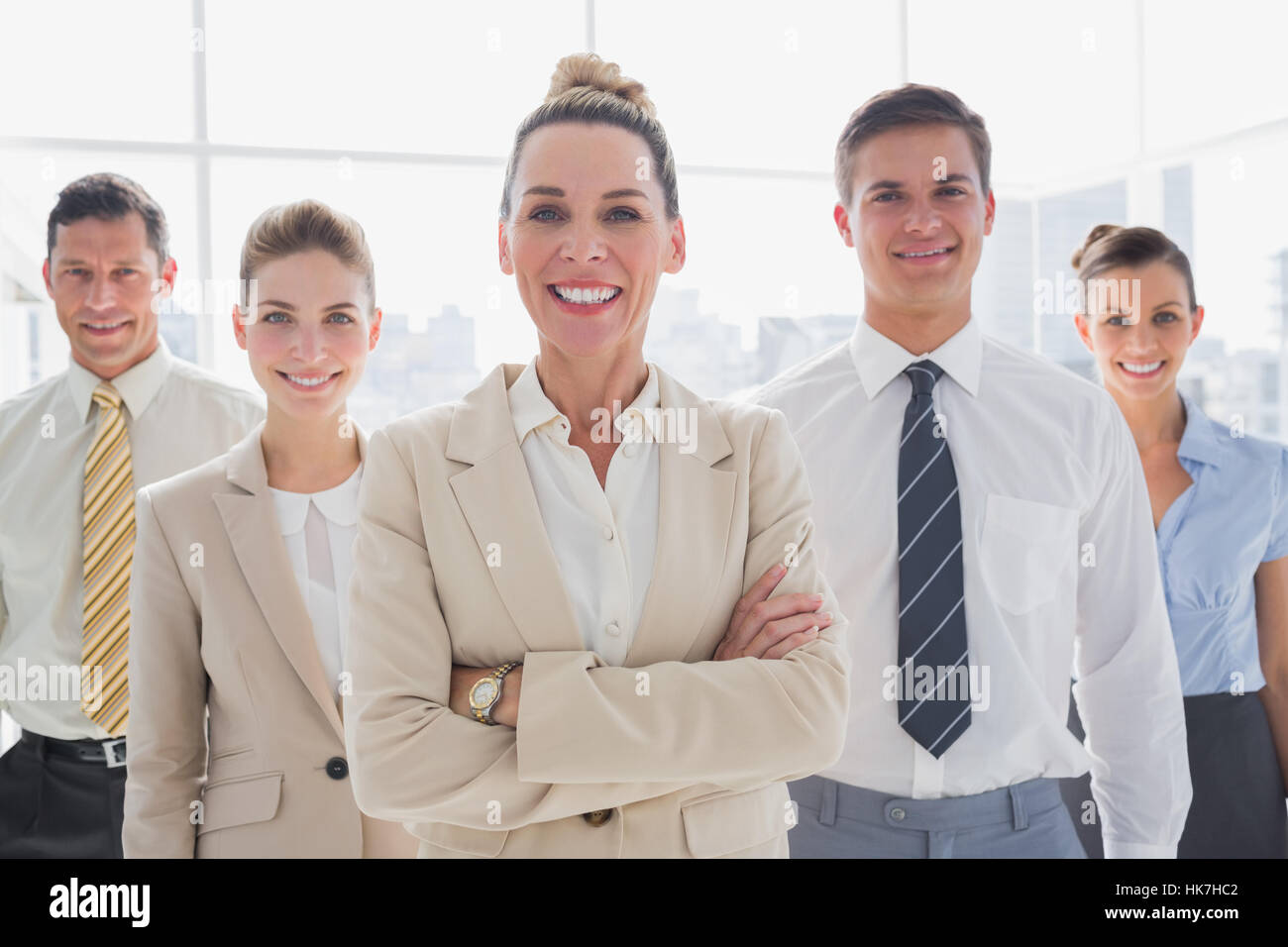 Group of smiling business team standing together with their arms folded ...
