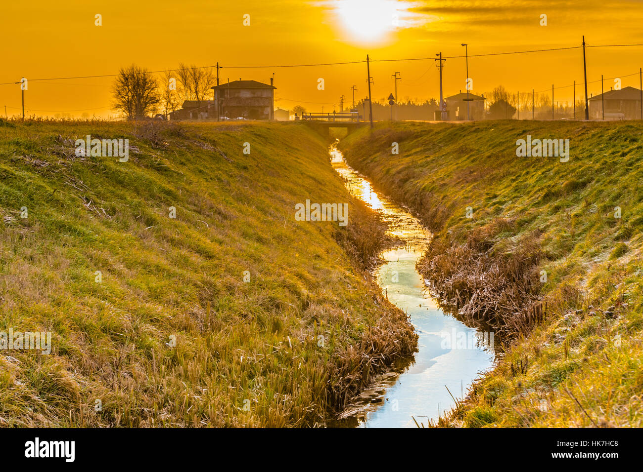 the dawn of the sun rising over an irrigation channel in the ...