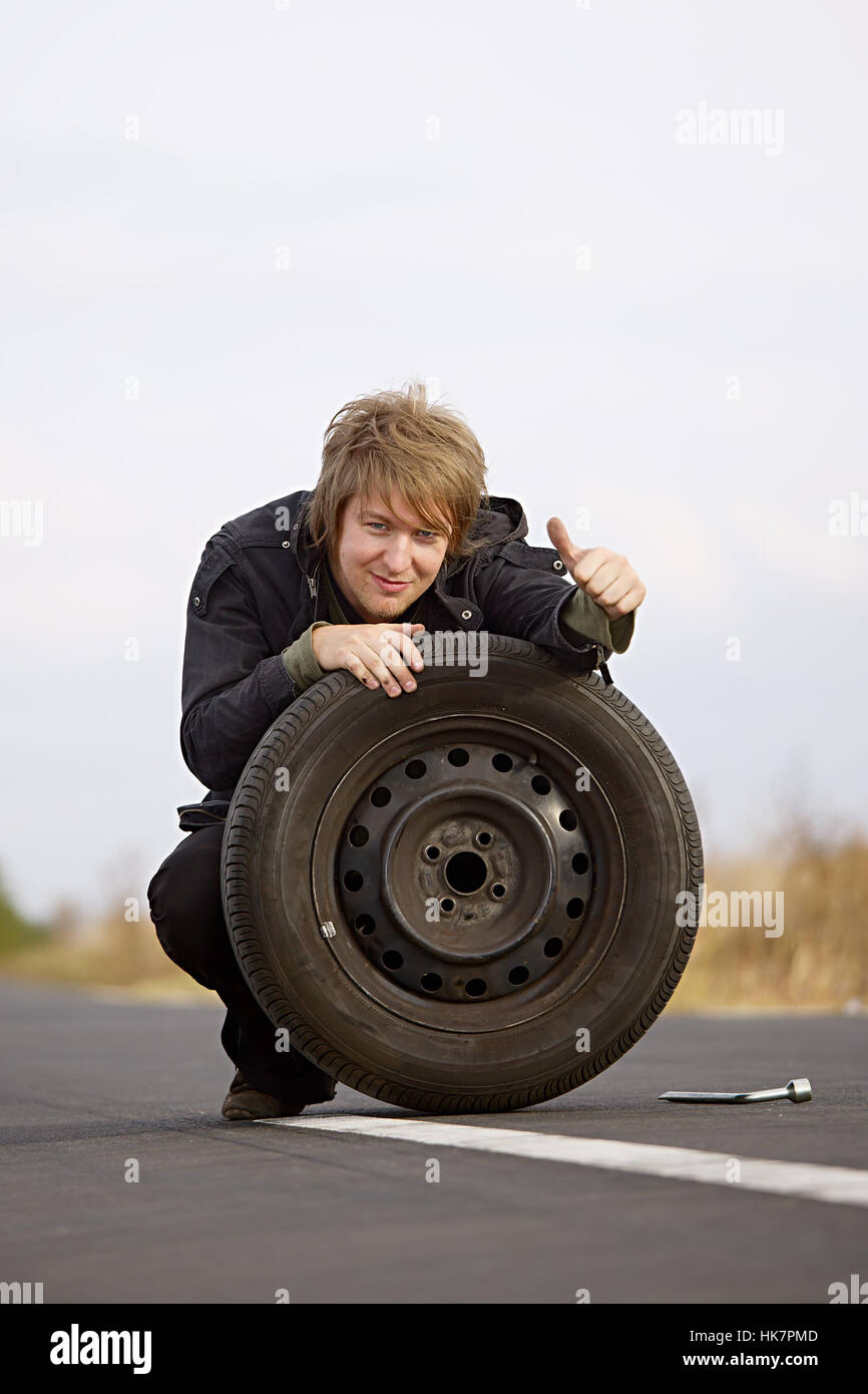 Man changing wheels being cheerful Stock Photo - Alamy
