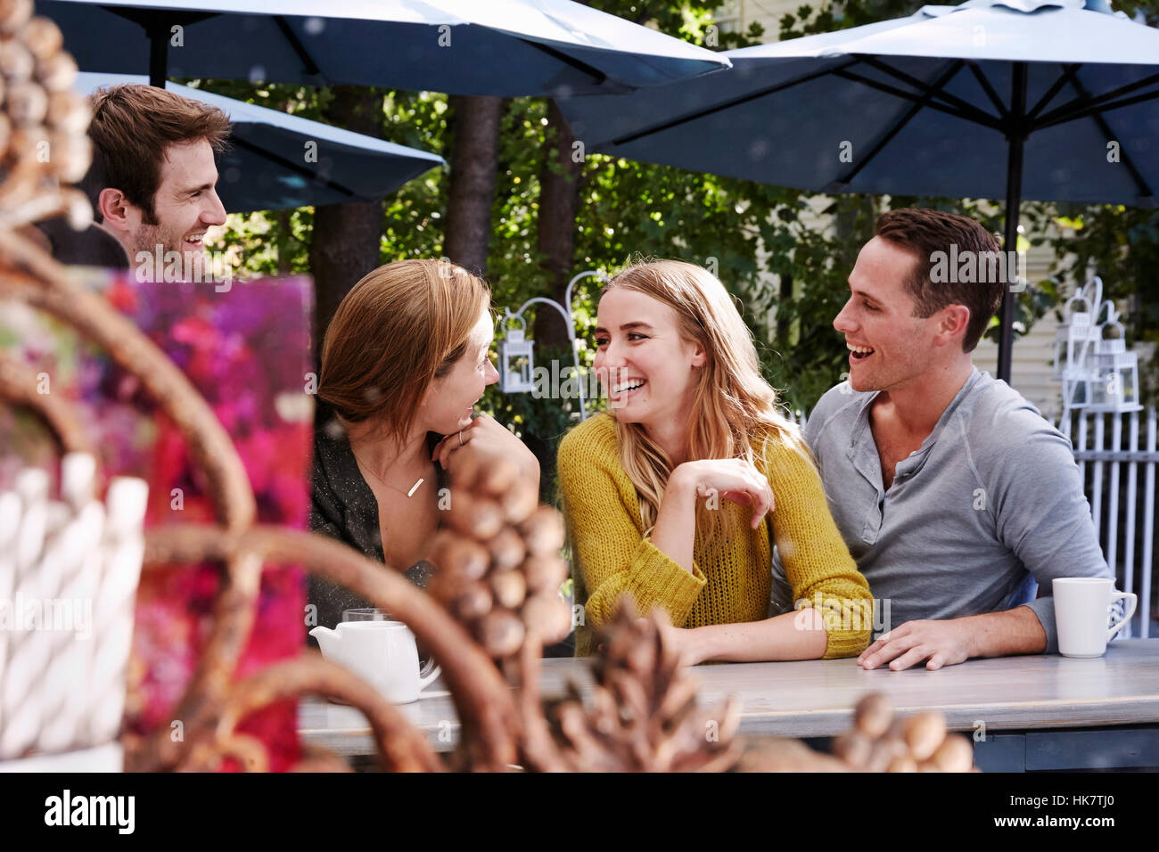 A group of people sitting at a long table in an outdoor cafe Stock ...