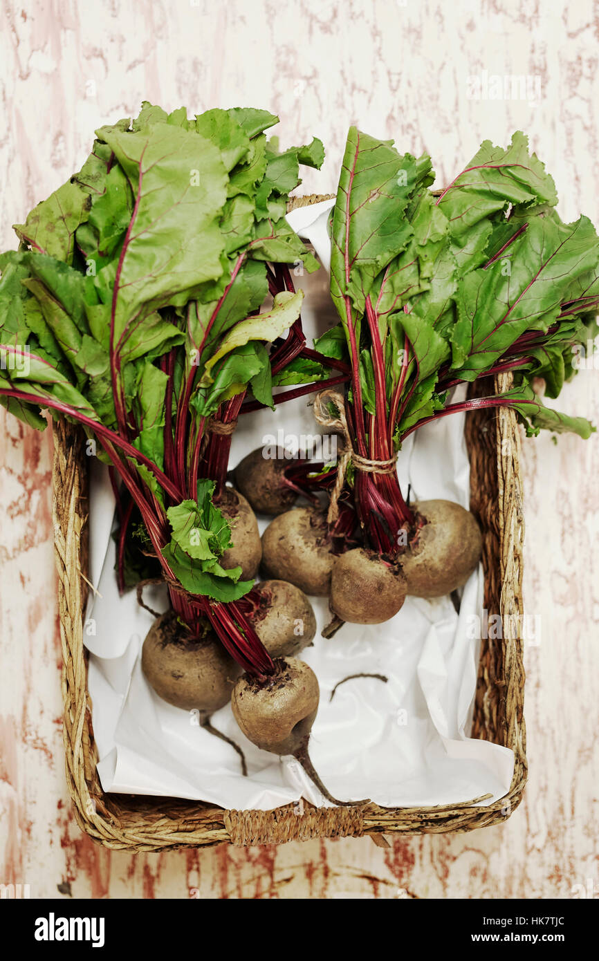 A shot of bundles of beets in a basket on a wooden surface, seen from ...