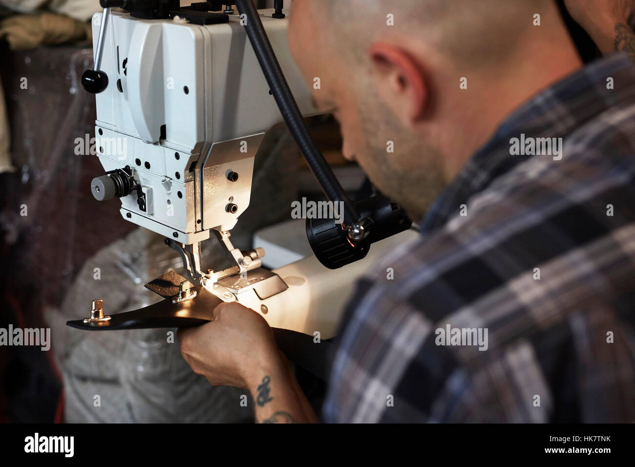 A man using an industriall sewing machine, stitching leather handmade ...