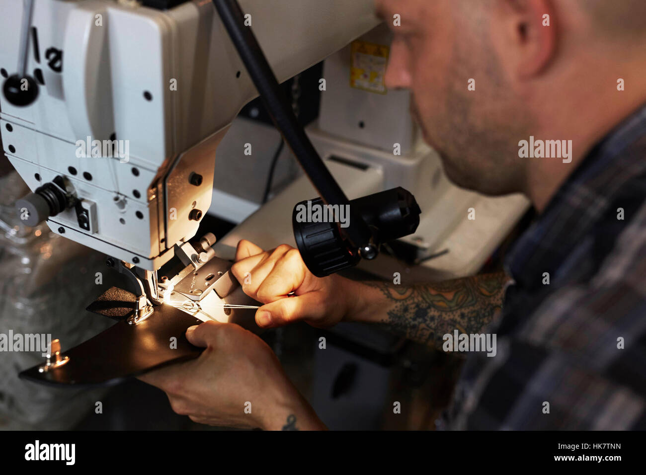 A man using an industriall sewing machine, stitching leather handmade ...