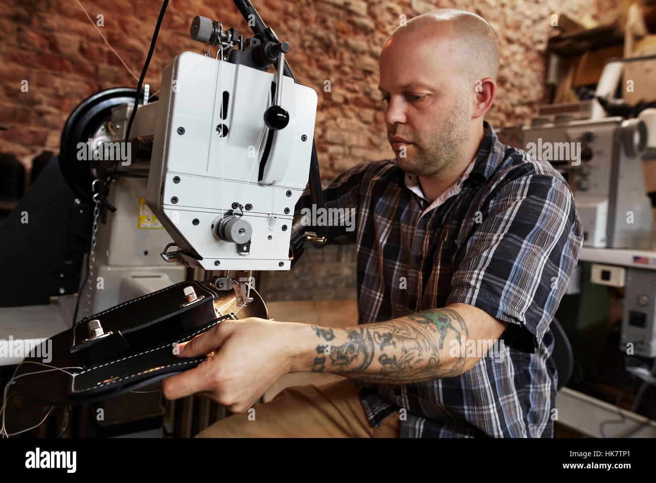 A leather worker, craftsman using an industrial sewing machine on ...