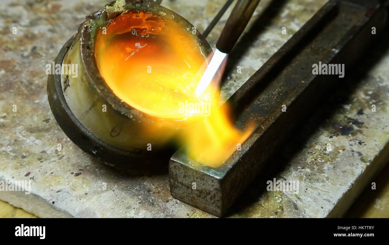 Molten metal, gold being poured into a mould for setting Stock Photo ...
