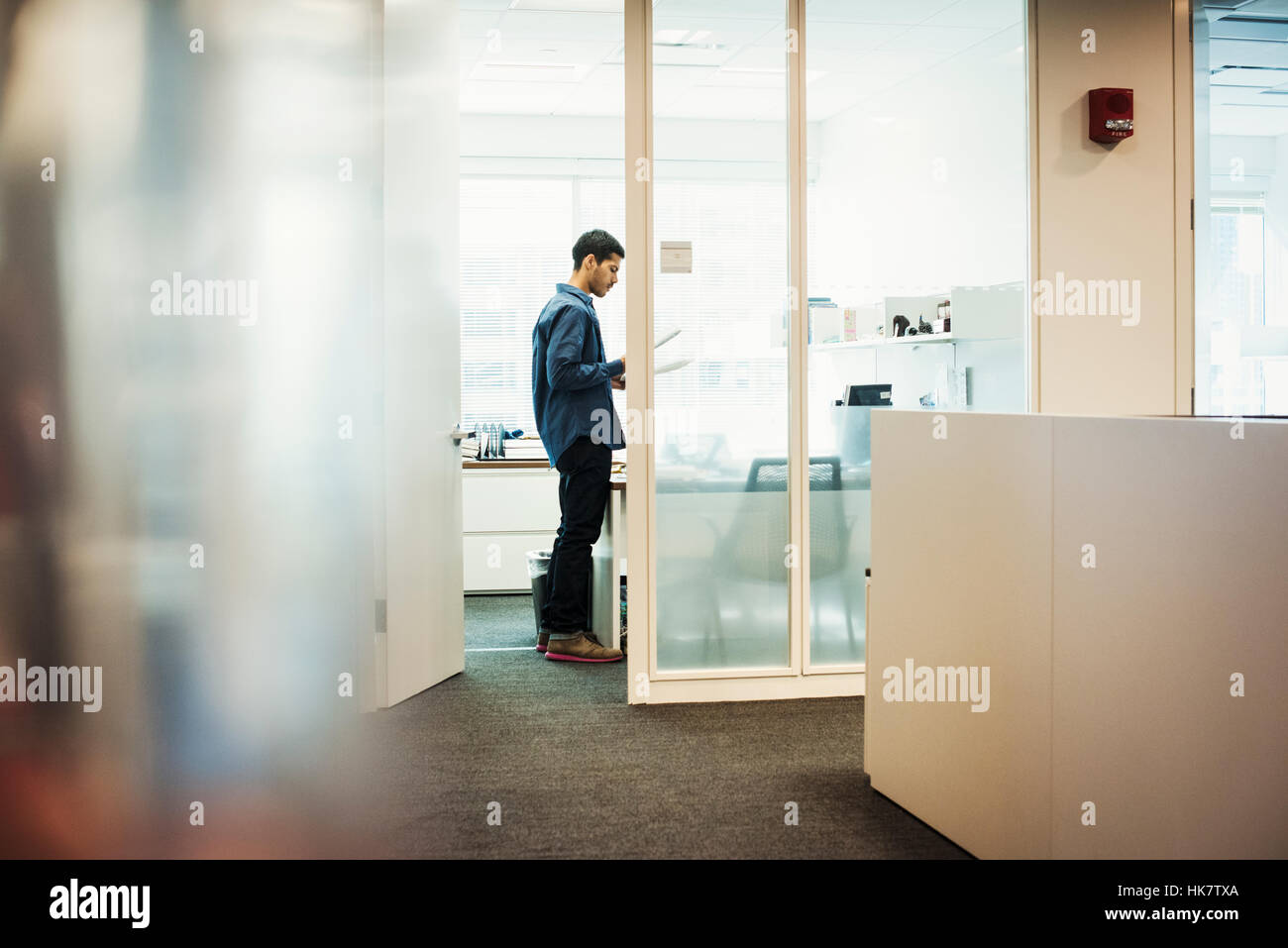 A man standing in an office looking down at pieces of paper Stock Photo ...
