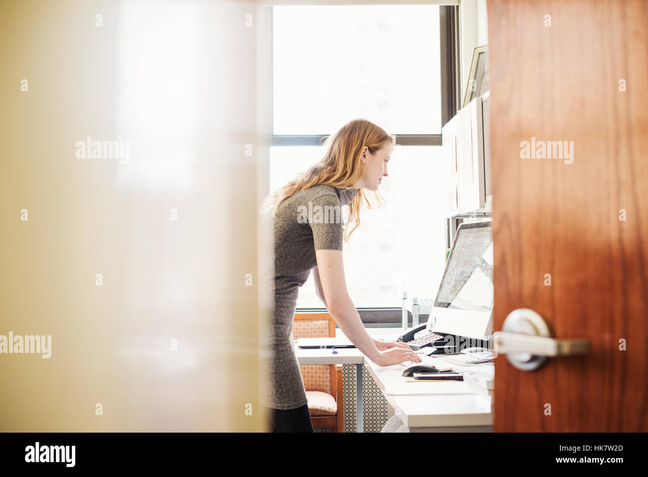 A woman in an office, seen through an open door Stock Photo - Alamy