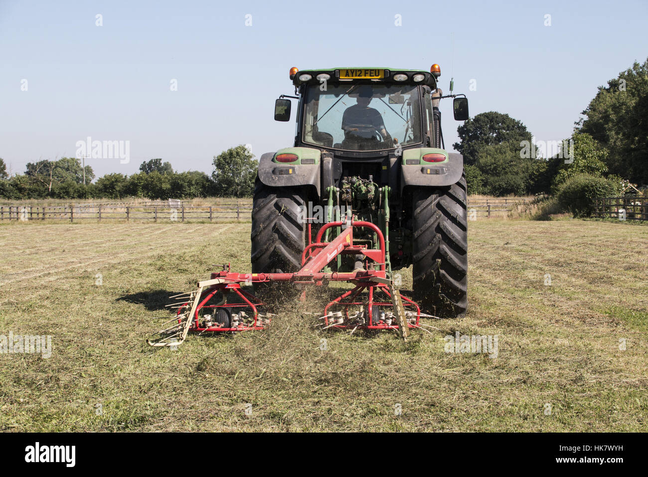 Haymaking, second stage, turning the cut grass using a twin rotor rake ...
