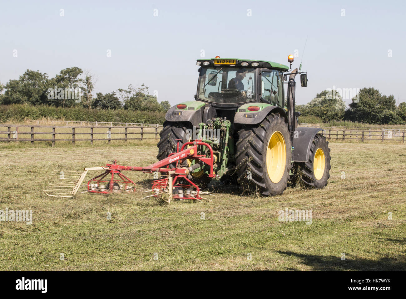 Haymaking, second stage, turning the cut grass using a twin rotor rake ...