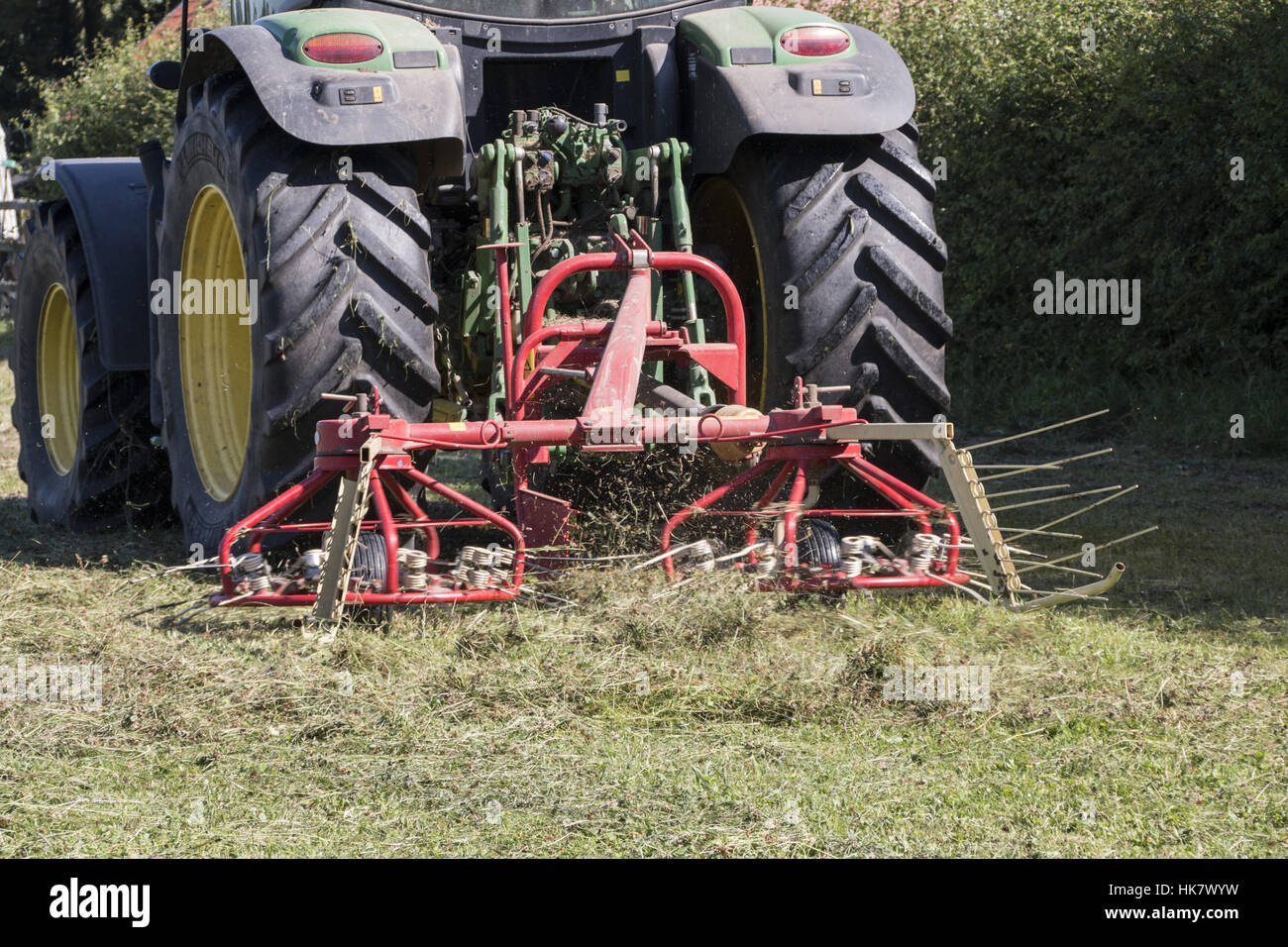 Haymaking, second stage, turning the cut grass using a twin rotor rake ...