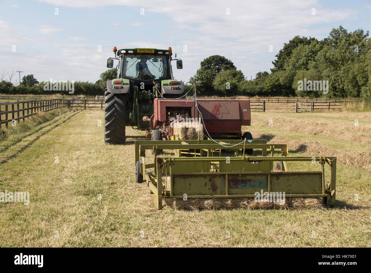Haymaking, third stage, tractor towing conventional baler and bale ...