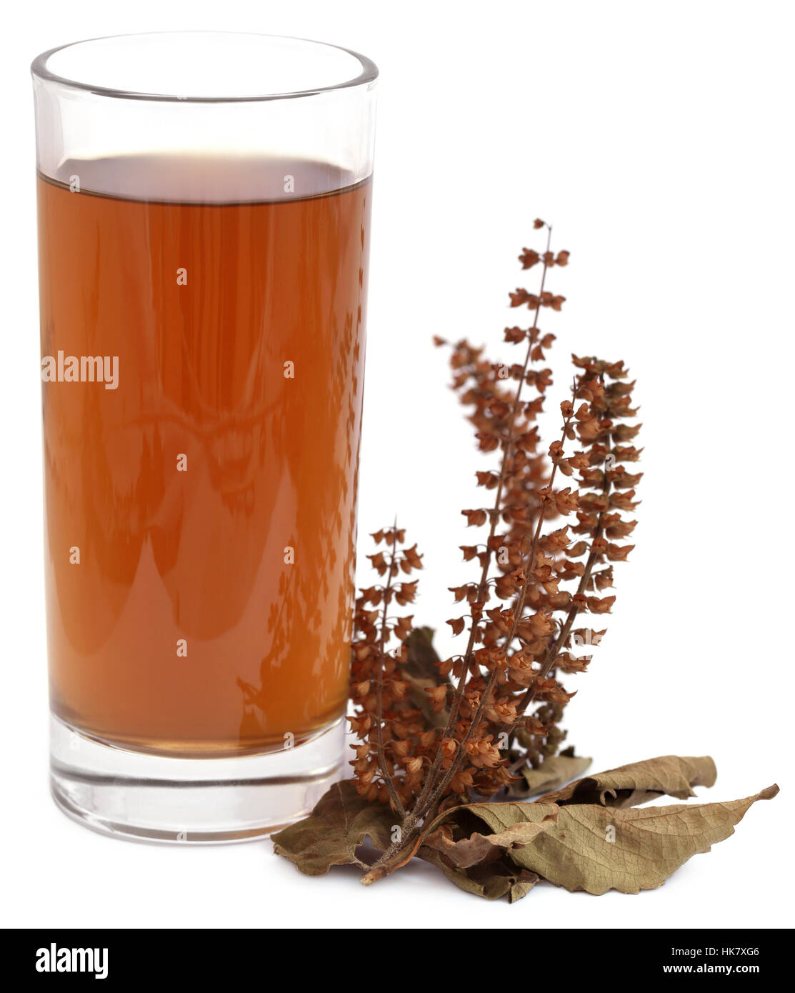 Juice with dry holy basil leaves and flowers over white background ...