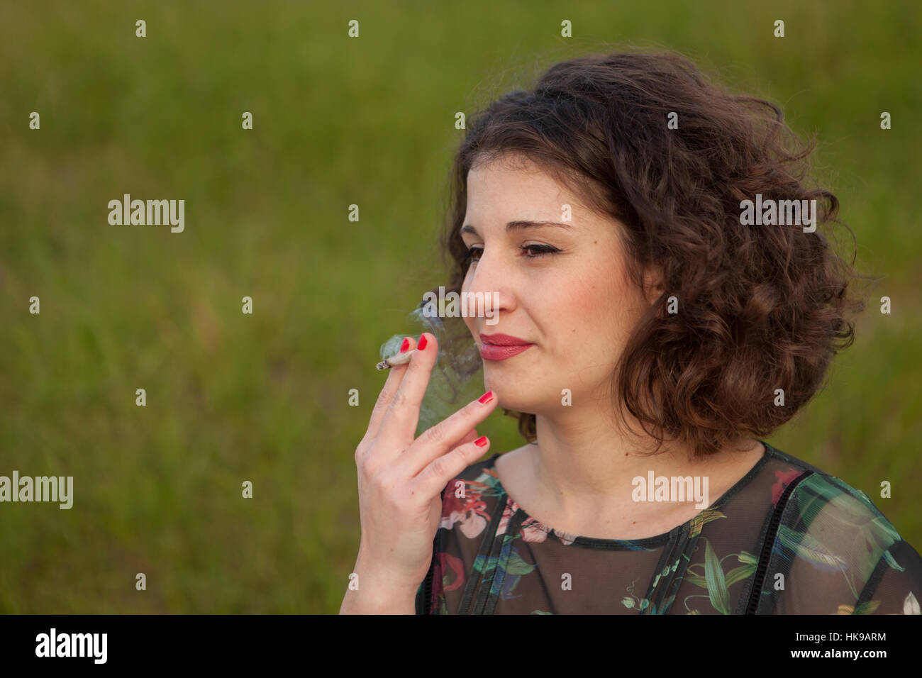 Casual young woman smoking a cigar in the landscape Stock Photo - Alamy