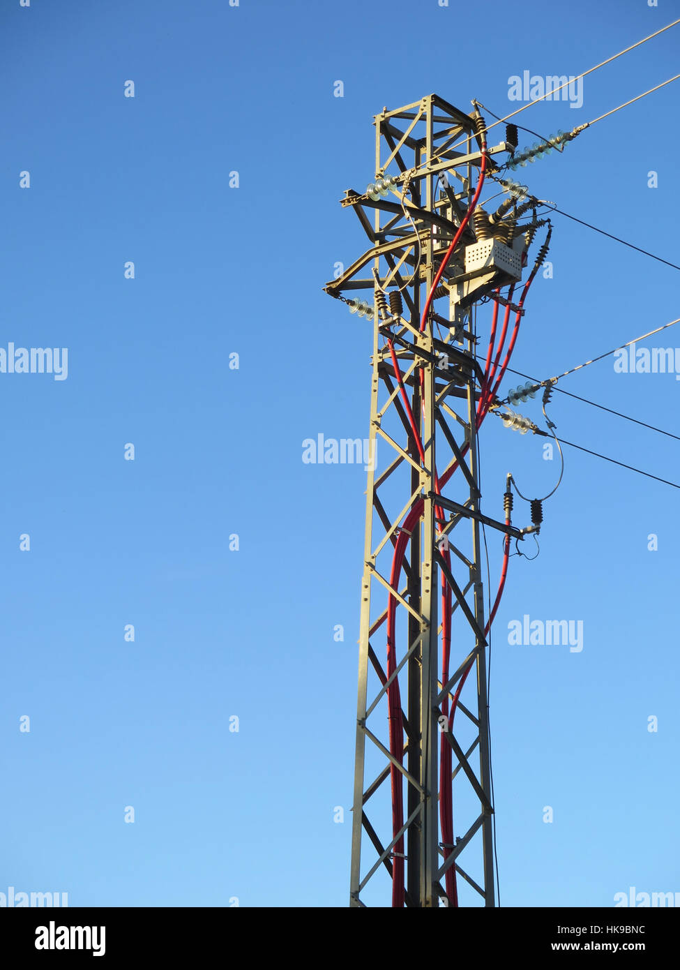 Steel pylon with red power cables against blue sky Stock Photo - Alamy