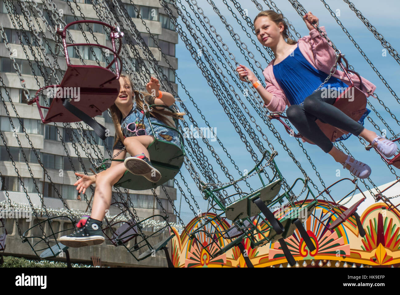 Two teenage girls sitting on the carousel with a tower block in the ...