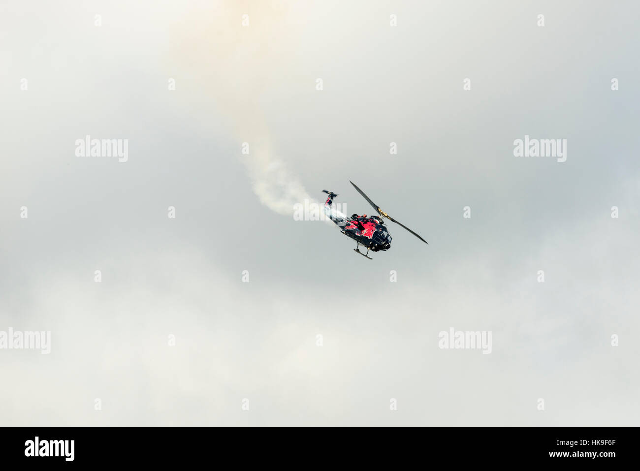 A helicopter, releasing smoke, is performing stunts in the air Stock ...