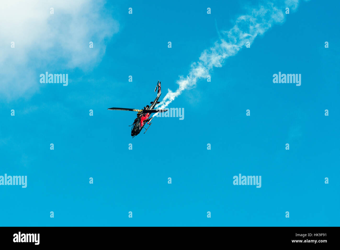 A helicopter, releasing smoke, is performing stunts in the air Stock ...