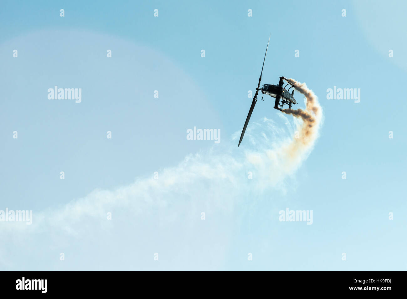 A helicopter, releasing smoke, is performing stunts in the air Stock ...