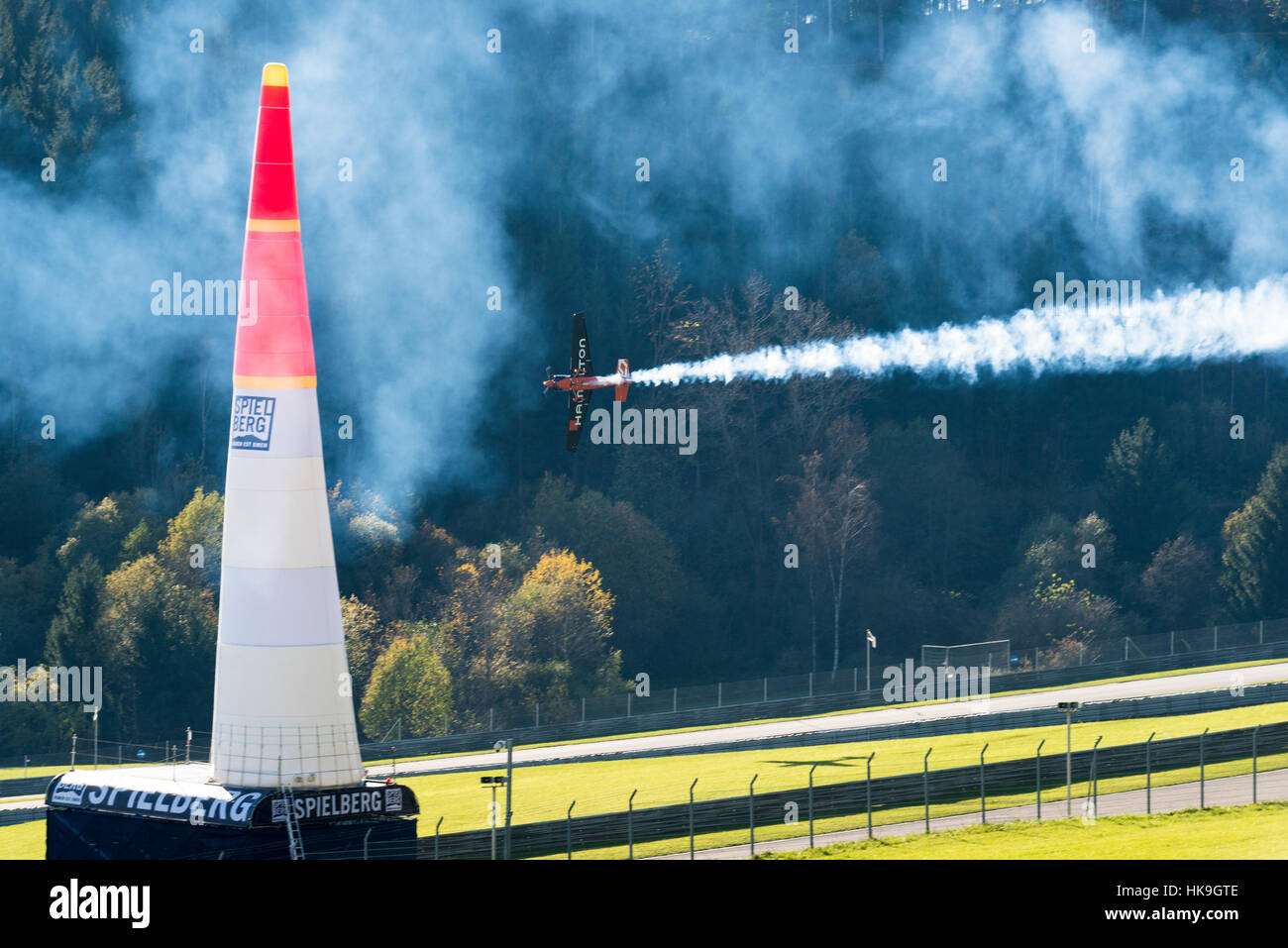 A stunt flying aeroplane, releasing smoke, is flying vertically around ...