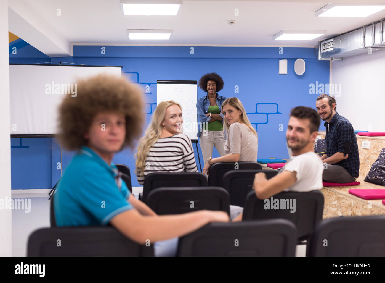 Portrait of smiling young informal businessman with colleagues in ...