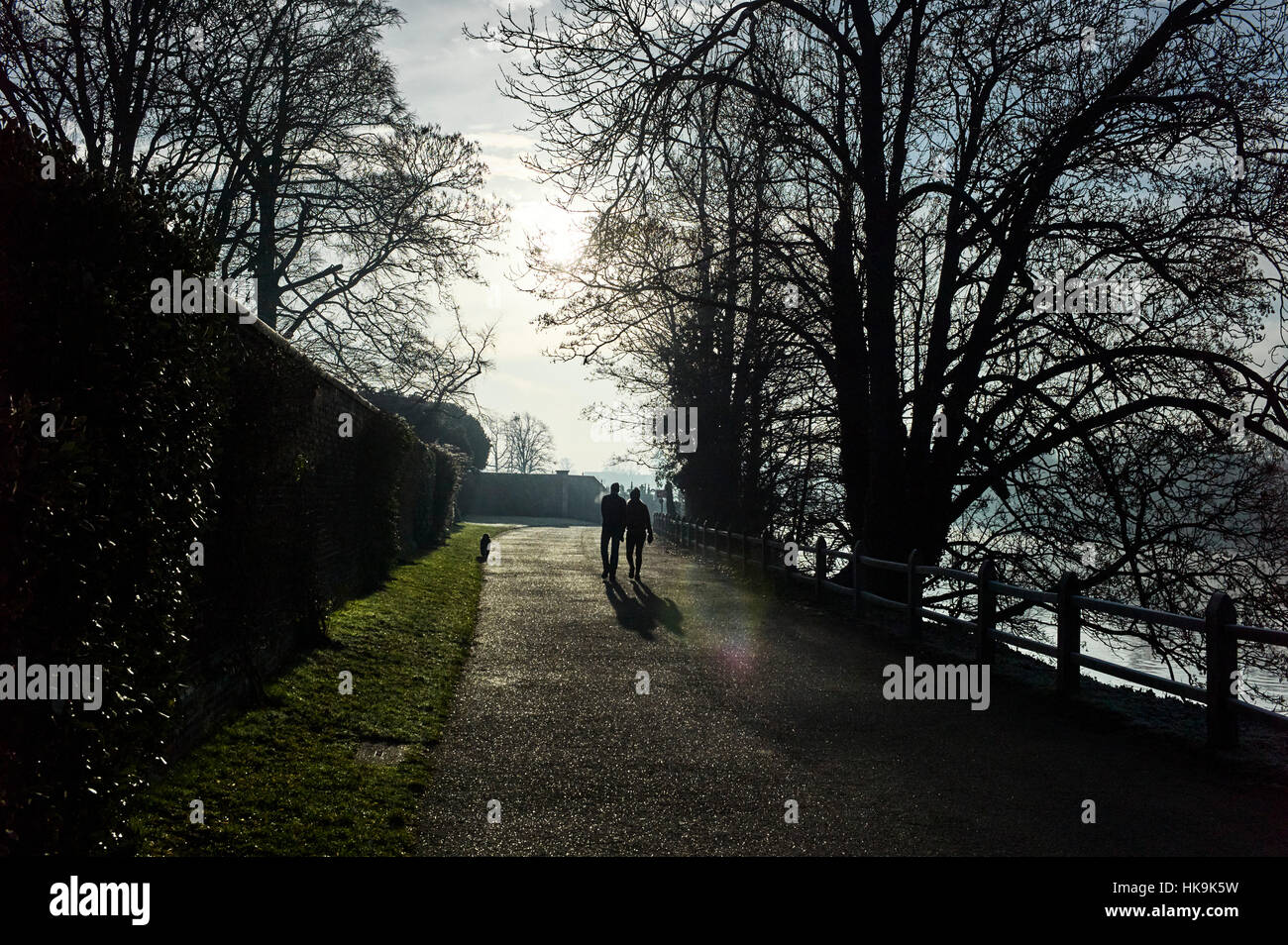 Two people walking dog on cold frosty morning Stock Photo - Alamy