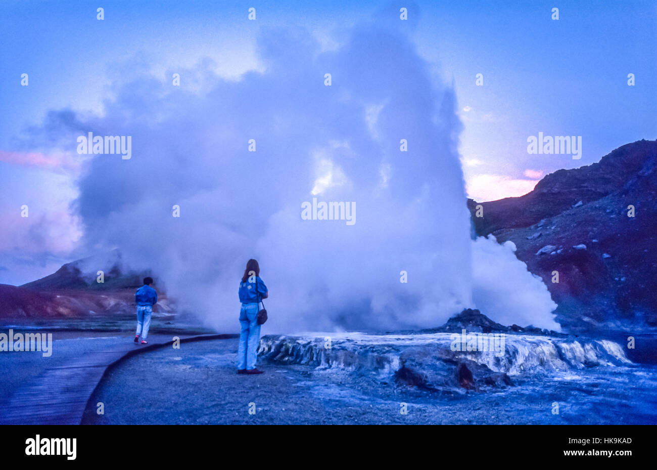 Tourists visiting geysers at nighttime on midsummer's night in Iceland ...