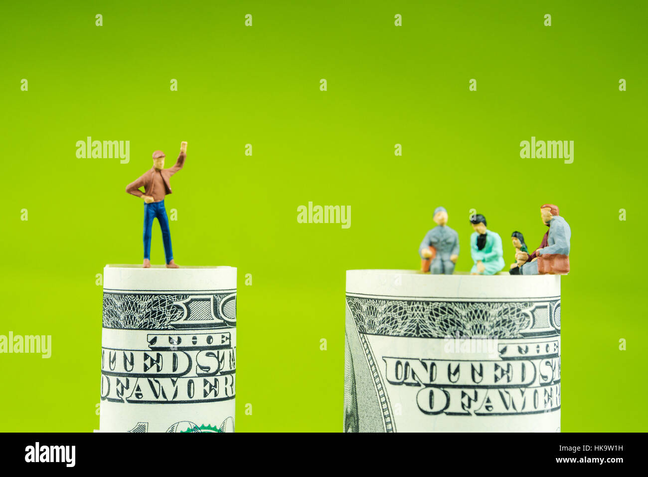 miniature figurines sitting on the edge of 100 dollar banknote on green ...
