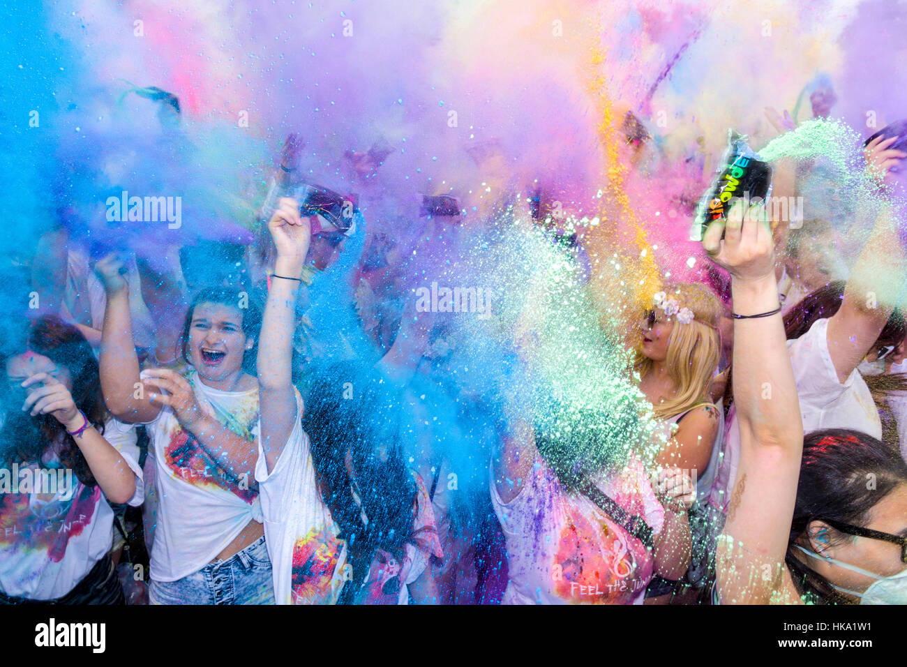 Thousands of young women and man are throwing color powder in the air ...