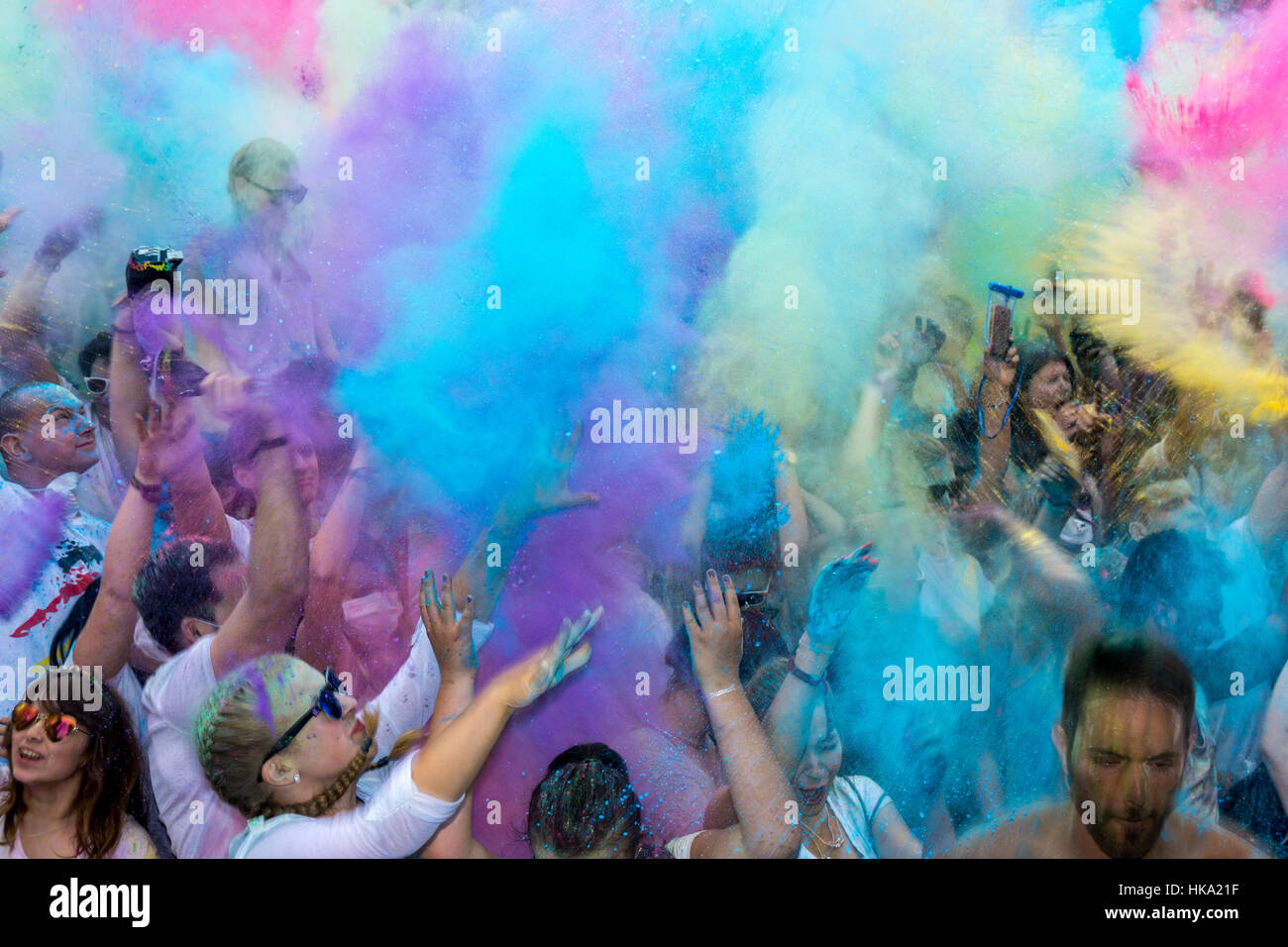 Thousands of young women and man are throwing color powder in the air ...